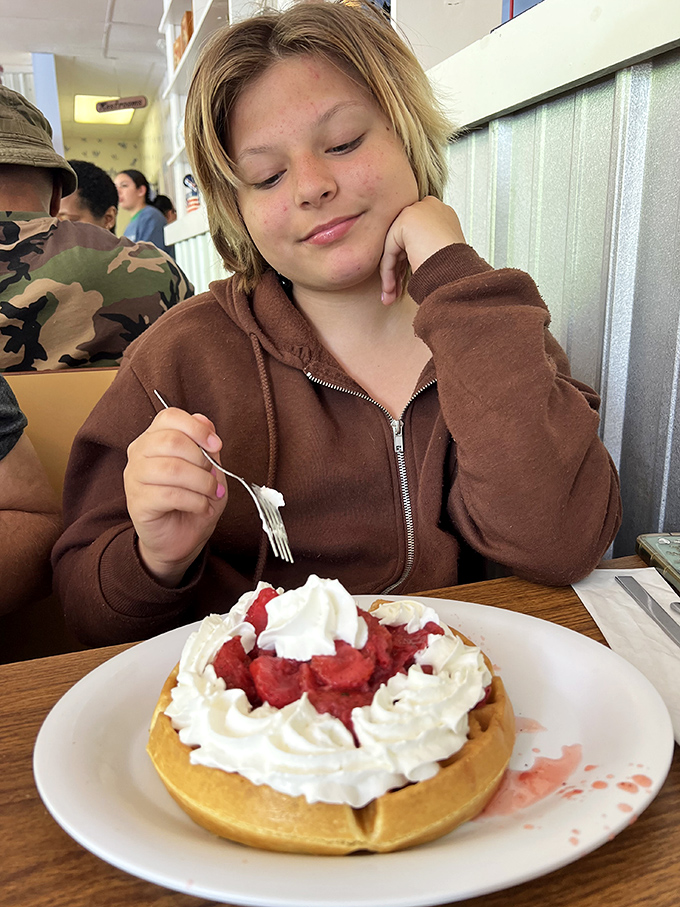 The look of breakfast bliss captured mid-bite. That strawberry waffle topped with whipped cream mountains isn't just dessert disguised as breakfast &ndash; it's pure joy on a plate.