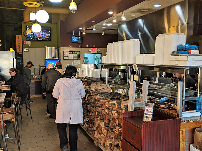 The open kitchen concept lets you witness the smoky magic. That stack of firewood isn't decoration&mdash;it's the secret ingredient.