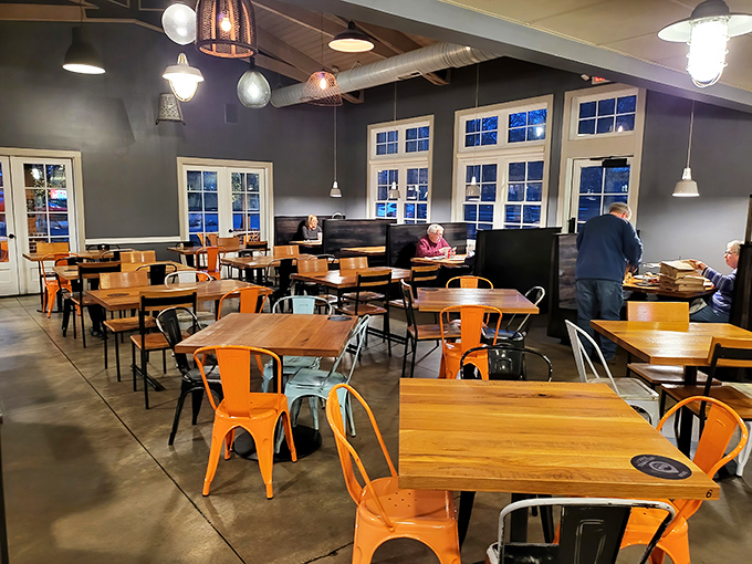 Orange chairs pop against gray walls in this dining space where every table feels like the best seat in the house.
