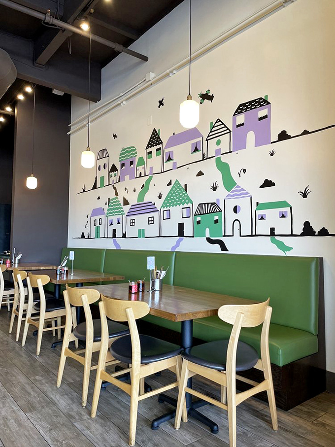 Whimsical wall art featuring purple and green houses creates a storybook backdrop for serious eating. The green banquette practically begs you to linger.