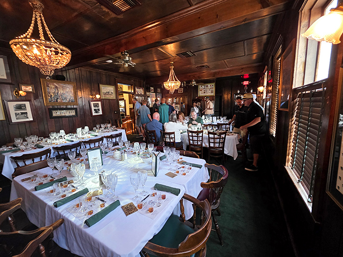 The dining room set for a special event, where crystal chandeliers cast the perfect glow over white tablecloths. Memories will be made here tonight.