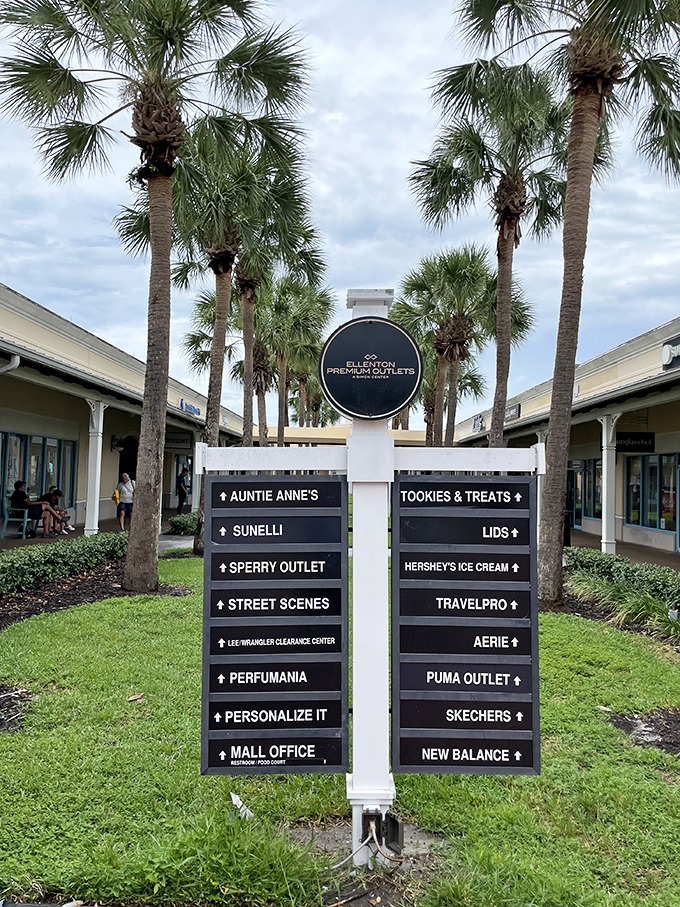 The directory sign stands like a retail treasure map beneath swaying palms, guiding bargain hunters to their next designer discovery.