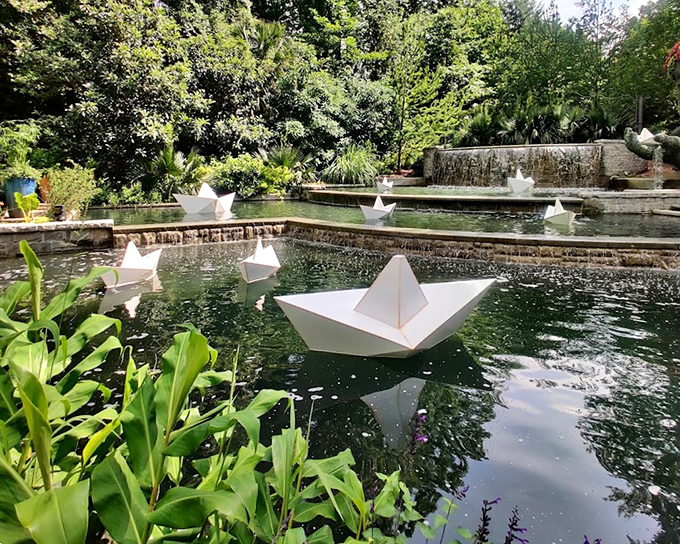 A fleet of origami boats sails across still waters, proving that sometimes the simplest art installations create the most magical moments.