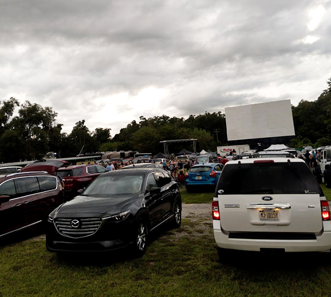 Cars gather under moody Florida skies as the iconic white screen awaits dusk's embrace &ndash; a scene unchanged since drive-ins first captured America's heart.