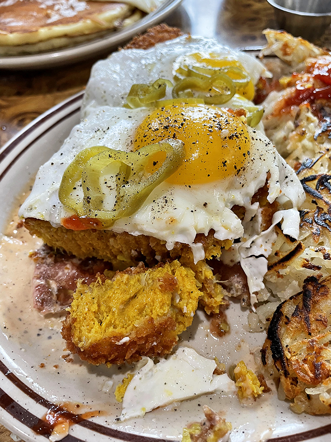 A sunny-side up egg perched atop what appears to be cornbread and scrapple&mdash;proof that breakfast architecture should be taught in design schools.