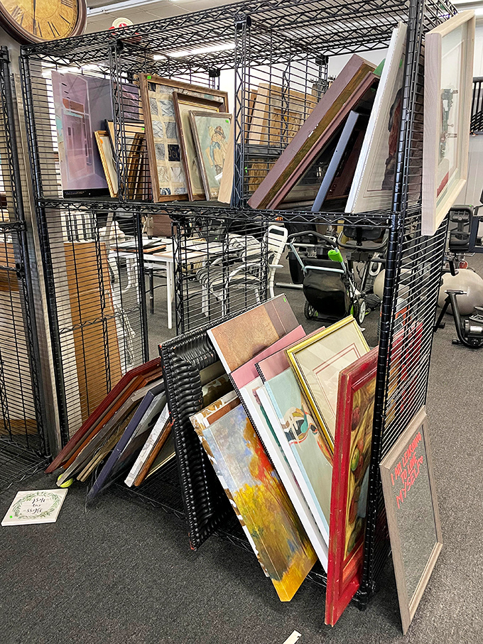 Framed artwork stacked like a gallery's back room, where masterpieces and paint-by-numbers peacefully coexist in democratic display.