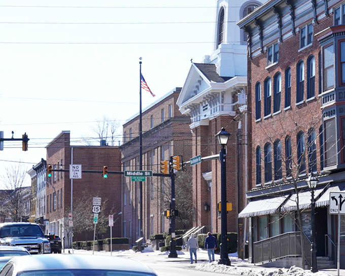 Historic brick buildings line Gettysburg's downtown streets, where American flags flutter above sidewalks that have witnessed over 150 years of history.