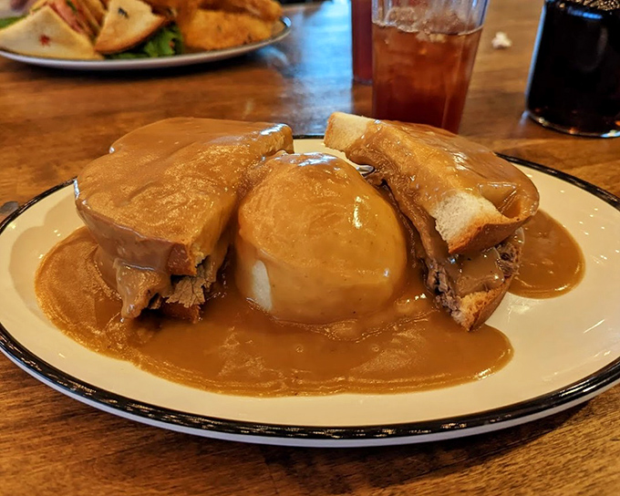 Hot beef sandwich swimming in gravy like a delicious life raft in a sea of comfort.