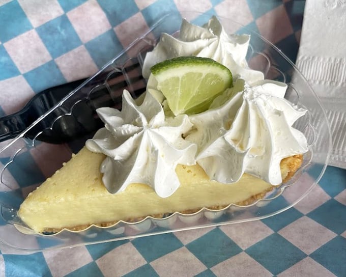 Key lime pie with a cloud of whipped cream that deserves its own weather report. The lime garnish is just showing off at this point.