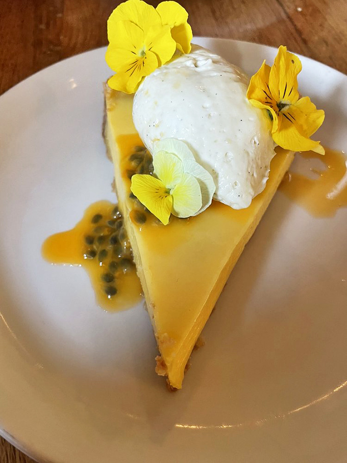 A slice of passion fruit tart adorned with edible flowers – because sometimes dessert should look like a painting and taste like a tropical vacation.