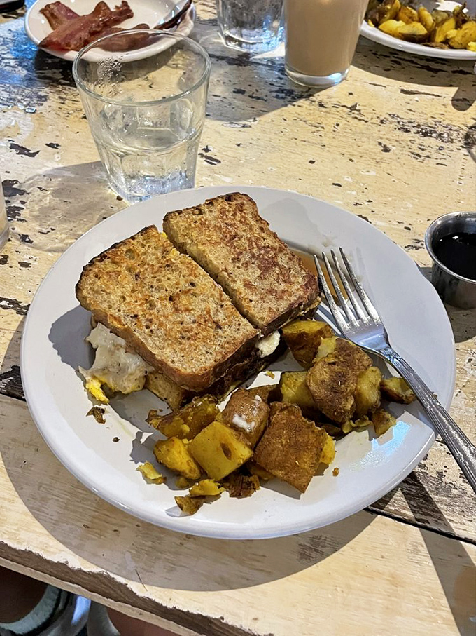 Breakfast sandwich perfection&mdash;golden-toasted bread hugging what appears to be eggs and cheese, with seasoned potatoes playing a delicious supporting role.