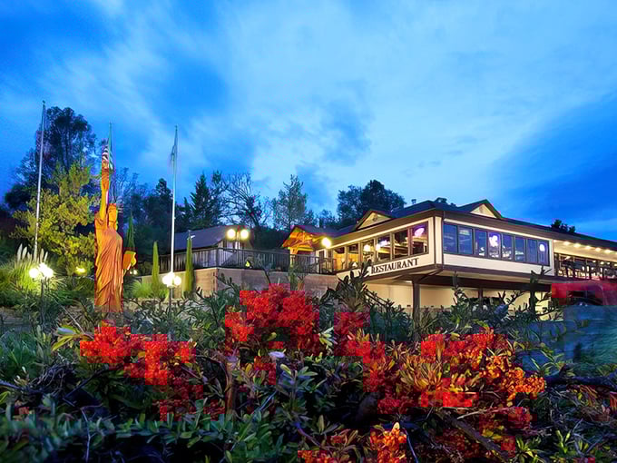 Twilight transforms Oakhurst Grill into a postcard-perfect scene, complete with Lady Liberty statue and blooming flowers&mdash;small-town dining with unexpected flair.