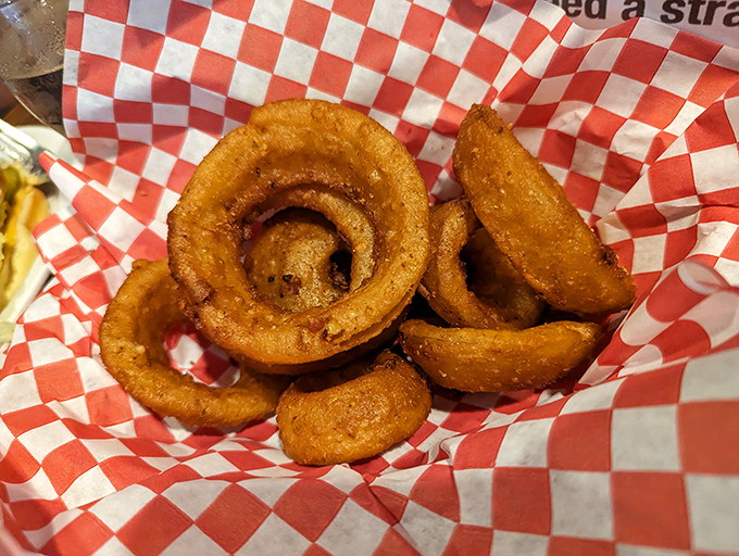 Onion rings with the perfect crunch-to-softness ratio, served in a red checkered basket that screams "American classic."