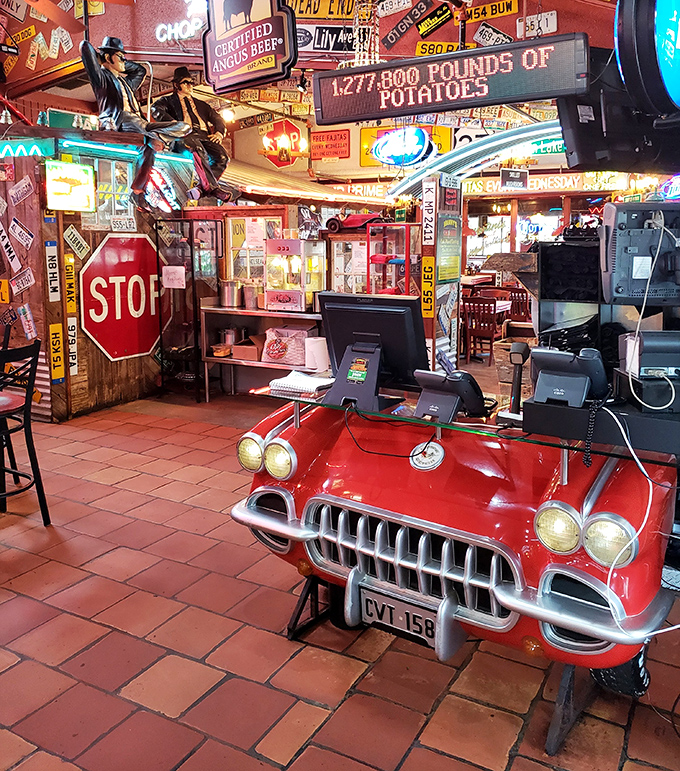 The front counter doubles as automotive memorabilia showcase—where a vintage Corvette front end serves as the perfect greeting station for hungry guests.