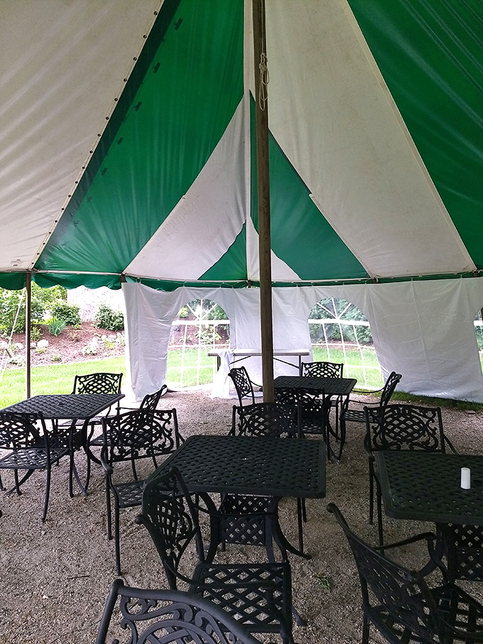 The green and white tent creates an outdoor dining oasis where summer breezes complement the feast, proving good food tastes even better alfresco.