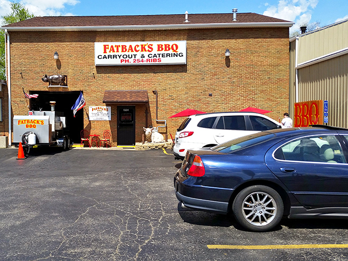 The parking lot view that signals you've arrived at your destination&mdash;where smoke signals and pig signs promise delicious things ahead.