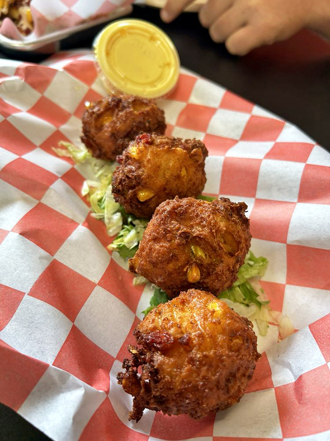 Golden-fried corn fritters studded with kernels of sunshine. These puppies aren't just pimped&mdash;they're royalty on a red-checkered throne.