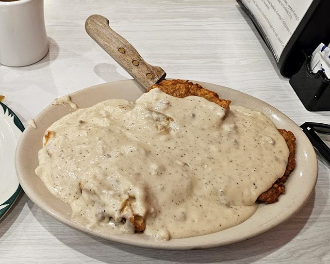 Country fried steak swimming in gravy&mdash;where the knife stands at attention in the middle like it's claiming this delicious territory for comfort food nation.