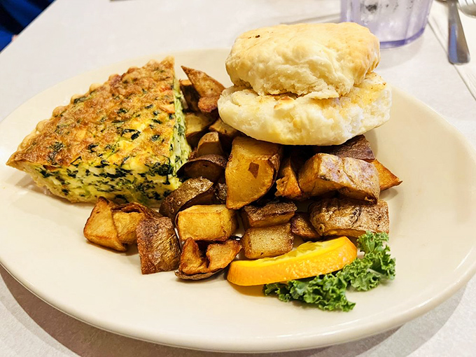 A quiche that doesn't apologize for its richness, paired with golden home fries and a biscuit that could make a carb-counter reconsider their life choices.