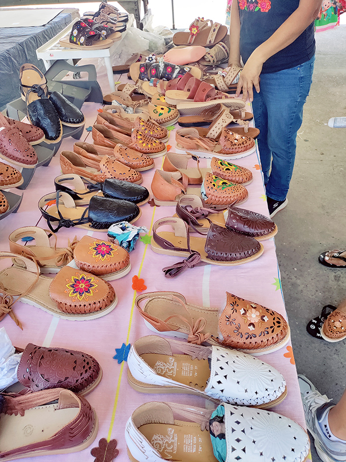 Handcrafted leather sandals line up like eager dancers, each pair telling a different story through intricate patterns and colors.