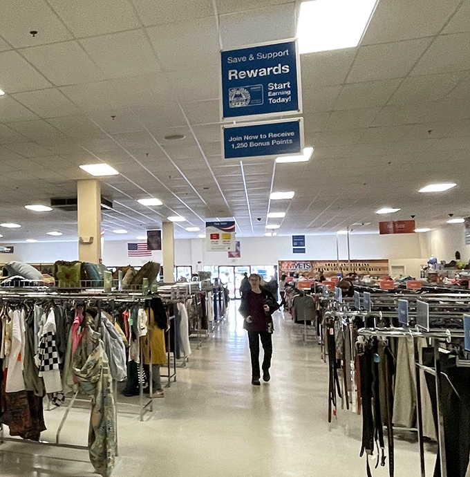 The rewards program sign hovers above shoppers navigating the clothing archipelago. The serious thrifters know exactly which aisles to hit first.