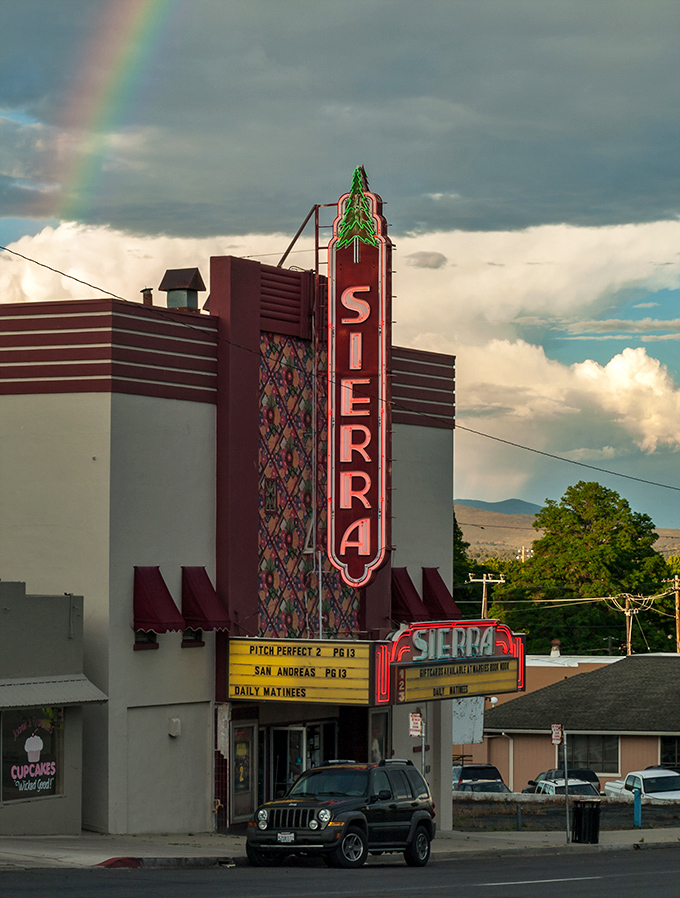 The Sierra Theater's neon sign glows against dramatic skies, offering affordable entertainment and the increasingly rare pleasure of watching movies with neighbors instead of algorithms.