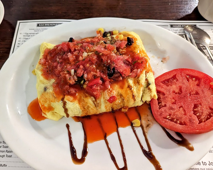 This omelet wears its salsa like a crown. The tomato slice stands guard, ensuring no bite goes unflavored in this Southwestern masterpiece.