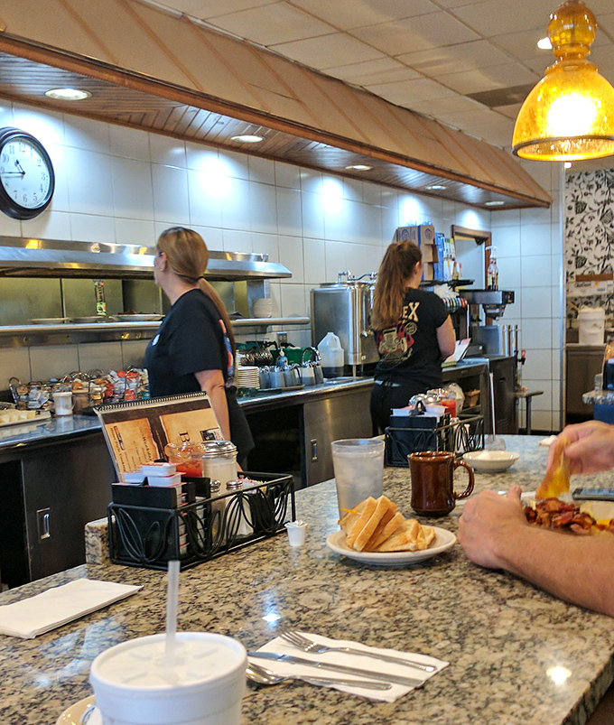 The counter seating offers front-row tickets to the kitchen show, where breakfast, lunch, and dinner happen simultaneously with practiced precision.