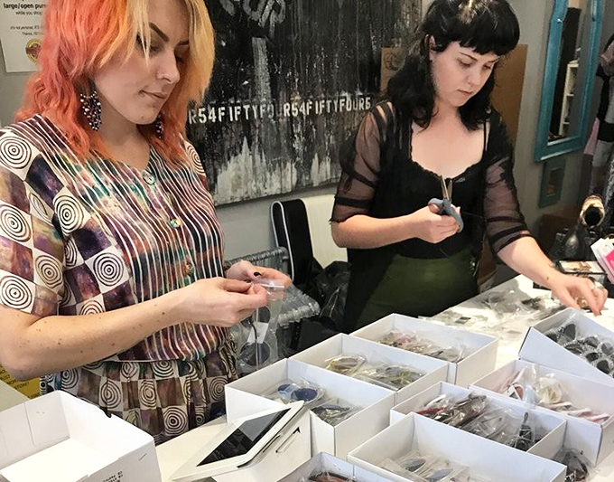 Shoppers examining jewelry boxes with the concentration of archaeologists discovering ancient treasures. Vintage shopping is serious business!