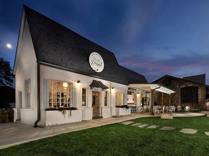 The Pure & Proper's elegant white facade glows at twilight, promising refined dining experiences. Like a Southern belle dressed in architectural form.