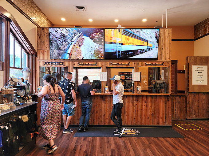 The ticket counter welcomes adventurers with rustic wood paneling and large screens previewing the journey—modern convenience wrapped in vintage charm.