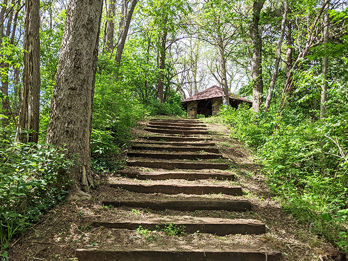 Stone steps ascending through a woodland sanctuary toward a historic shelter. The climb might leave you breathless, but so will the view waiting at the top.