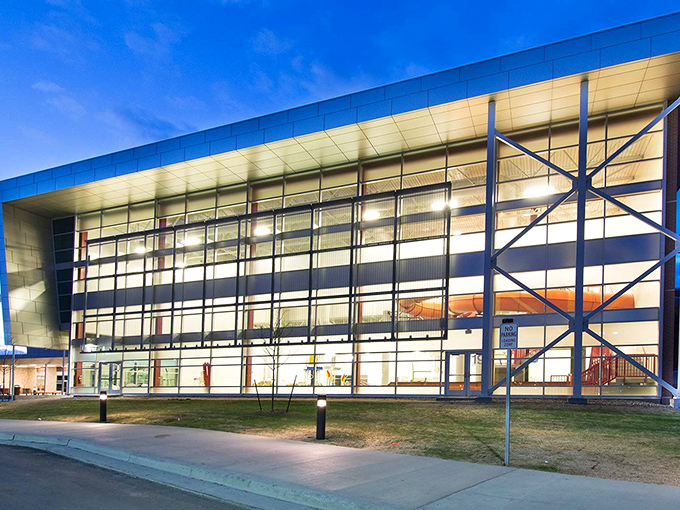 The Williston Area Recreation Center's striking modern architecture lights up the evening, a glass-fronted beacon of community wellness and activity.