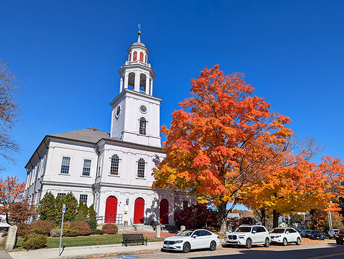 This classic New England church stands proudly against autumn's spectacular show, its white spire reaching skyward like an architectural exclamation point.
