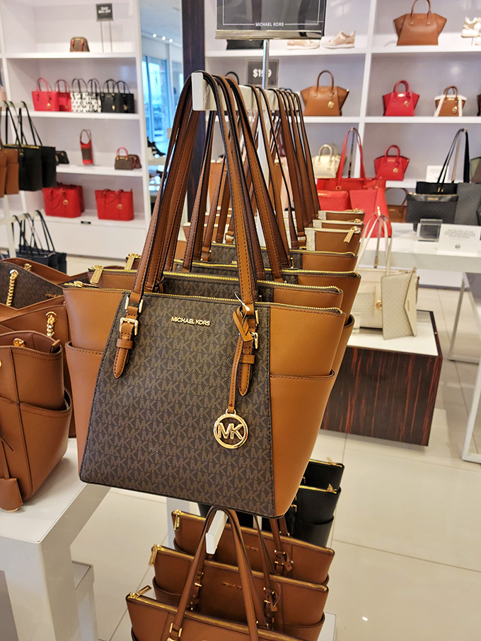 Michael Kors handbags lined up like soldiers ready for deployment to shoulders across the Midwest. Fashion's front line at outlet prices.