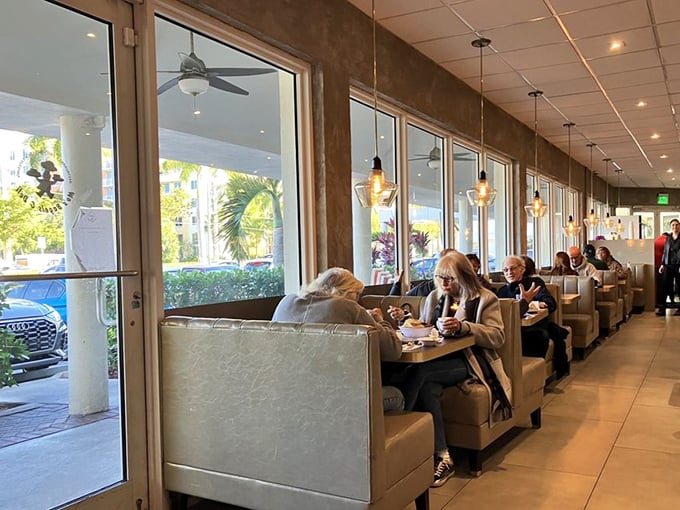 Floor-to-ceiling windows flood the dining area with natural light. These cozy booths have witnessed countless family gatherings, business deals, and first dates.