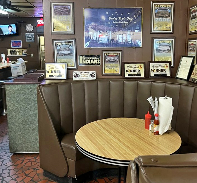 The booth section—where local sports memorabilia creates the perfect backdrop for conversations that flow as easily as the sweet tea refills.