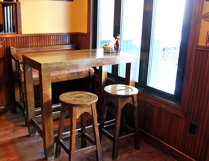 This cozy nook with its wooden high-top and stools isn't just seating &ndash; it's an invitation to linger over conversations that matter more than whatever's on your phone.