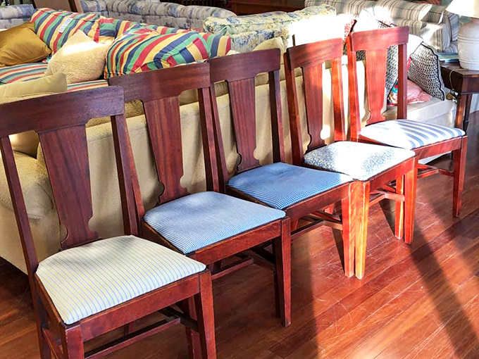 A lineup of dining chairs stands at attention, their wooden frames and varied upholstery ready to complete someone's perfect table setting.