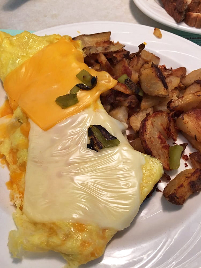 An omelet wearing a cheese blanket with roasted potatoes that clearly went to finishing school. Breakfast elegance at its finest.