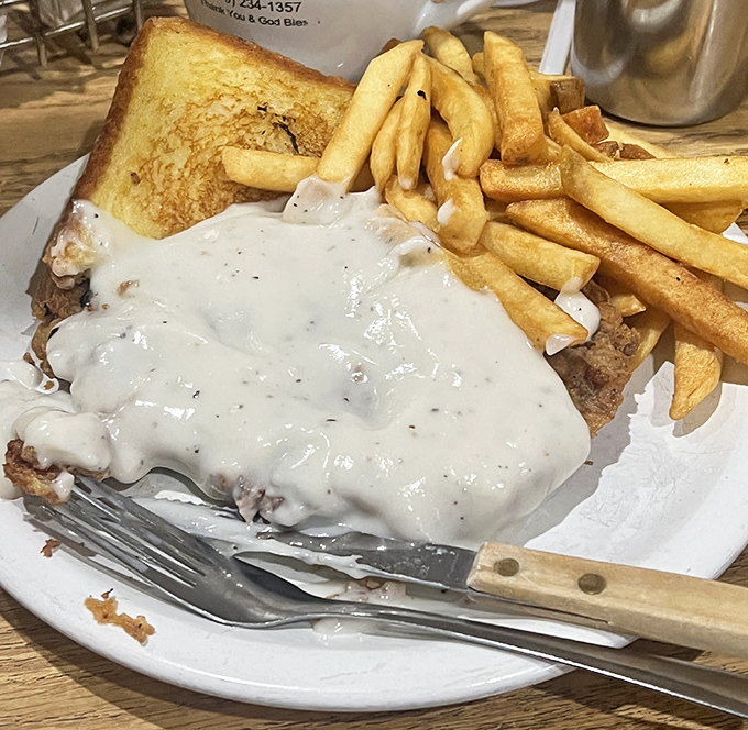 This chicken-fried steak sandwich smothered in country gravy isn't just comfort food&mdash;it's a warm, creamy hug on a plate with fries.