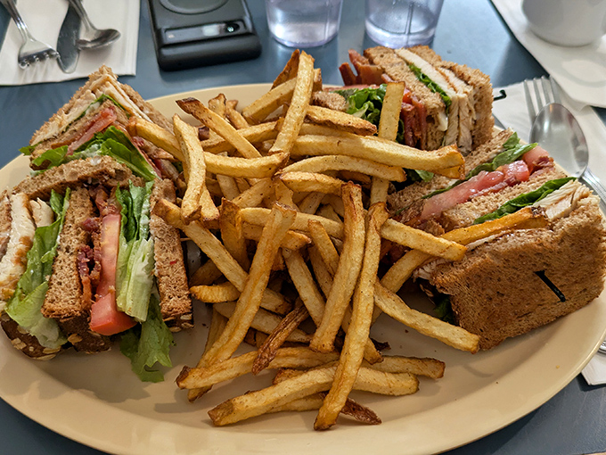 A club sandwich that requires jaw exercises beforehand, with fries so perfectly golden they deserve their own California postcard.