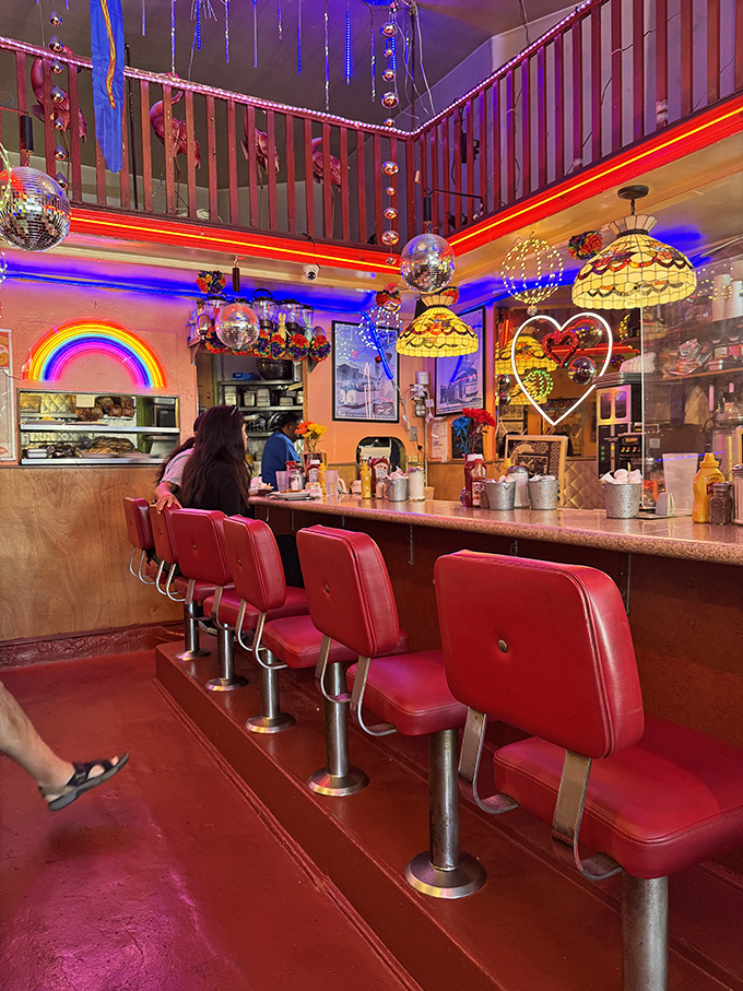 Red vinyl counter stools await their next patrons, while neon hearts and rainbows create the perfect backdrop for late-night confessions.