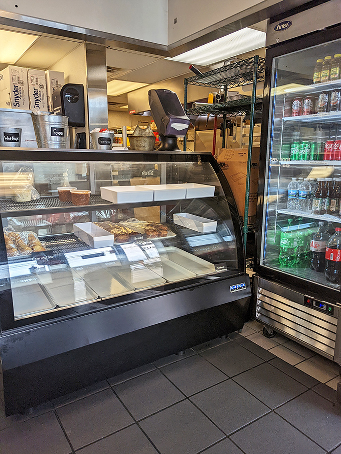The display case showcasing meats and sides with professional pride, proving presentation doesn't require marble countertops to impress.