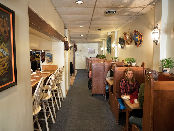 The dining room hums with conversation and satisfaction. These wooden booths have heard more Santa Fe stories than any tour guide.