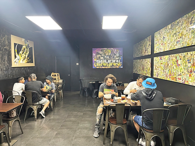 Real fans eating real food in a space that celebrates their passion. The dark walls make the colorful anime art pop like panels from a living comic book.