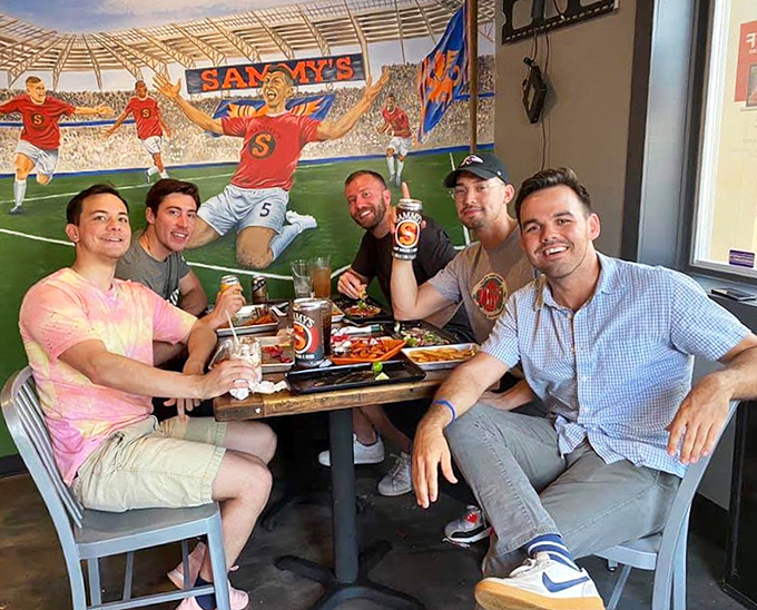 The universal truth of great food: it brings friends together. That mural in the background silently cheers on every bite and conversation.