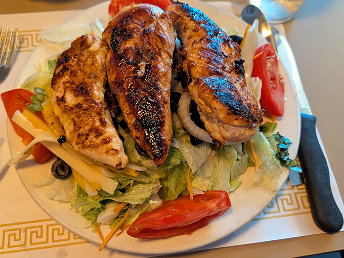 Grilled chicken with the perfect char marks lounges atop a salad that actually deserves to be called a meal, not a side thought.
