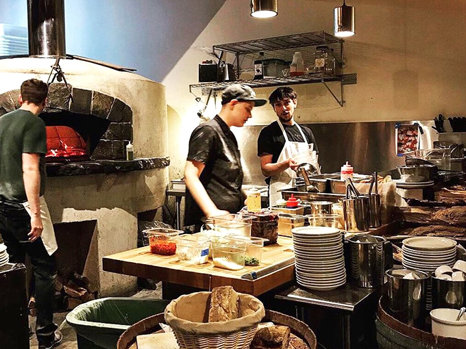 The kitchen's wood-fired oven is the beating heart of the bakery. These artisans are conducting a symphony of flour, water, and fire.