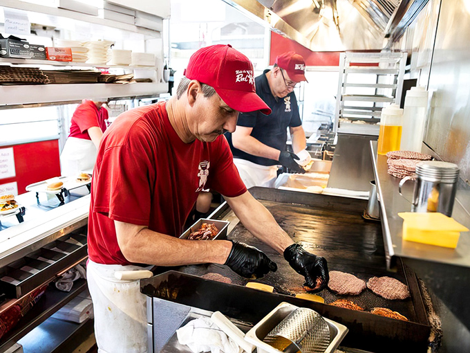 Burger artistry in action—where skilled hands transform simple ingredients into roadside masterpieces that have stood the test of time.